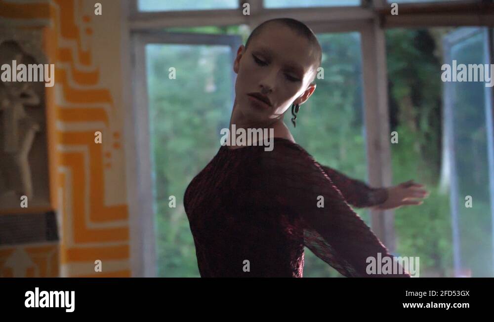 A mysterious young woman with shaved head is spinning around and ...