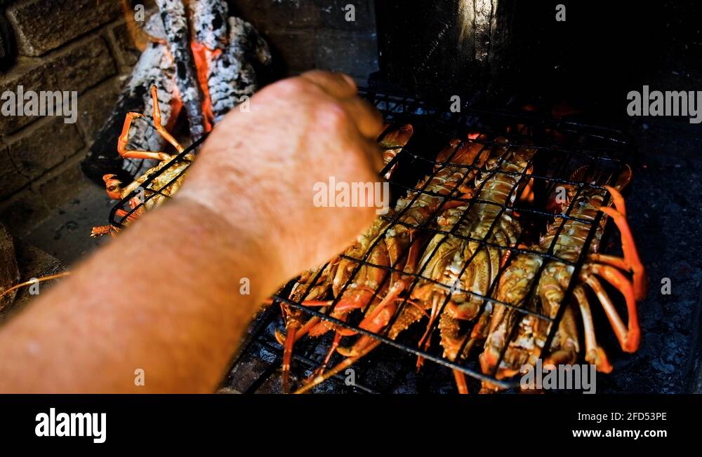 Crayfish on open fire being dressed with garlic-butter and barbecued on ...