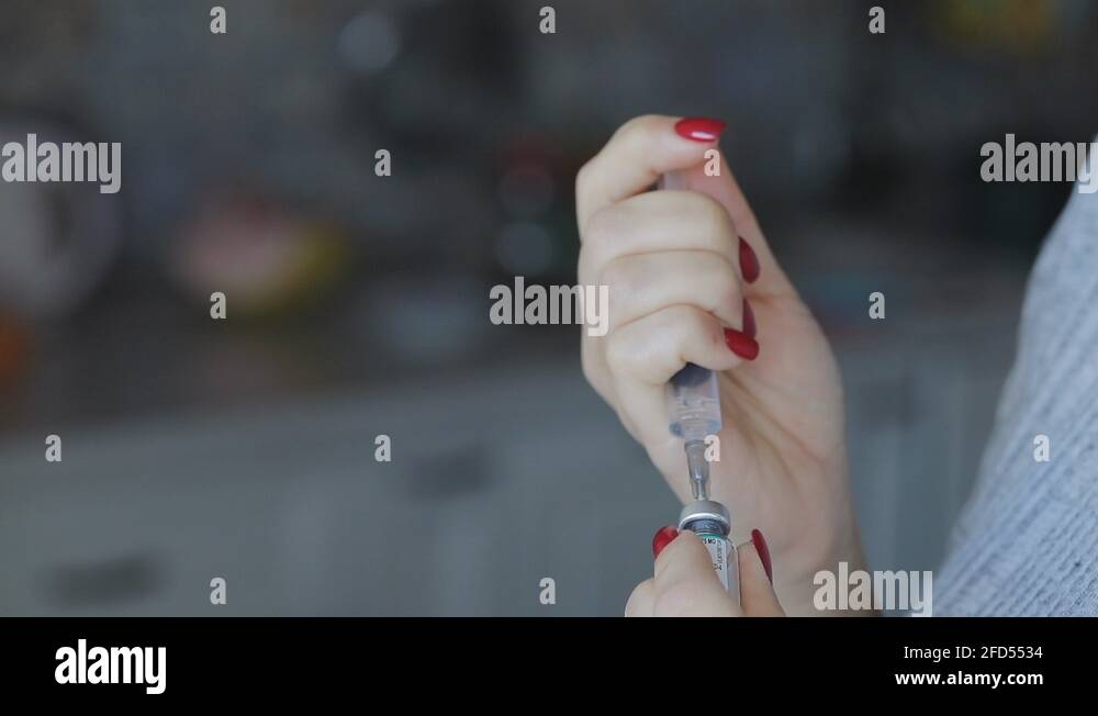 Girl picking up medication into a syringe and prepares it for injection ...