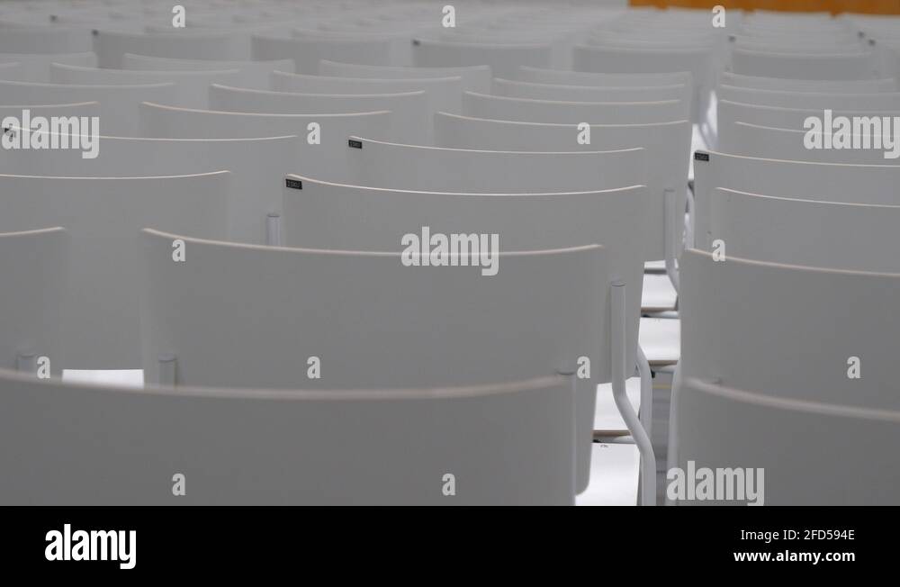 Lines of empty white seats, first spectator arrives, stands back up ...