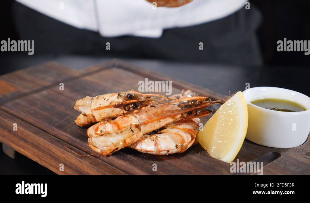 Professional chef cook serving dish with deep fried king prawns. Side ...