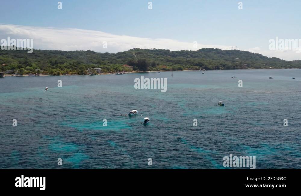 Rotating aerial over ocean reef with snorkling boats, island background ...