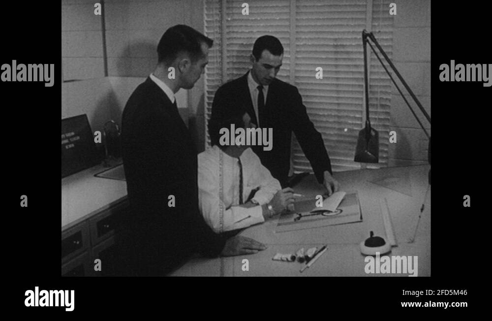 1960s: Three men have conversation around drafting table. Man looking ...