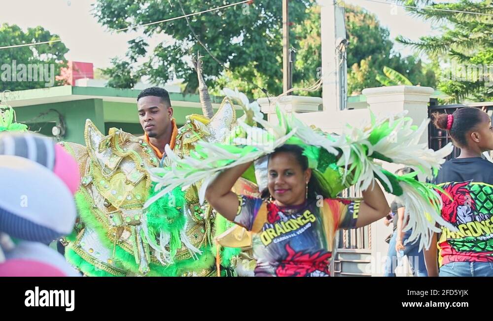 people in colorful carnival costumes walk on dominican city street at ...