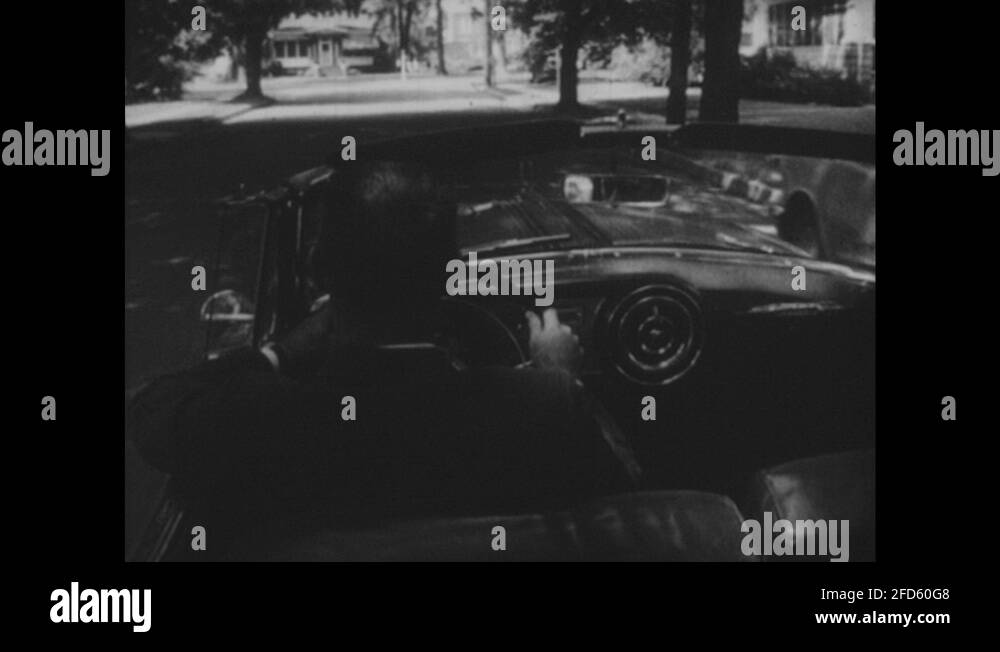 1950s: UNITED STATES: view of driver in car and road. Stop sign on road ...