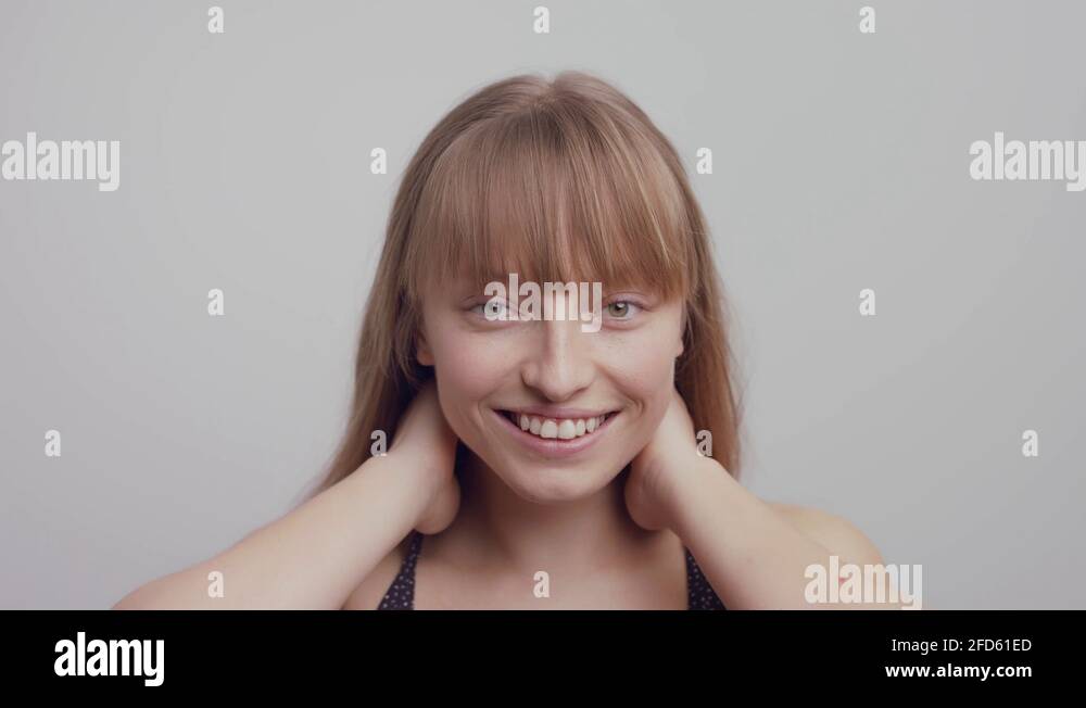 A beautiful woman flicking her hair with her hands frontwards while ...