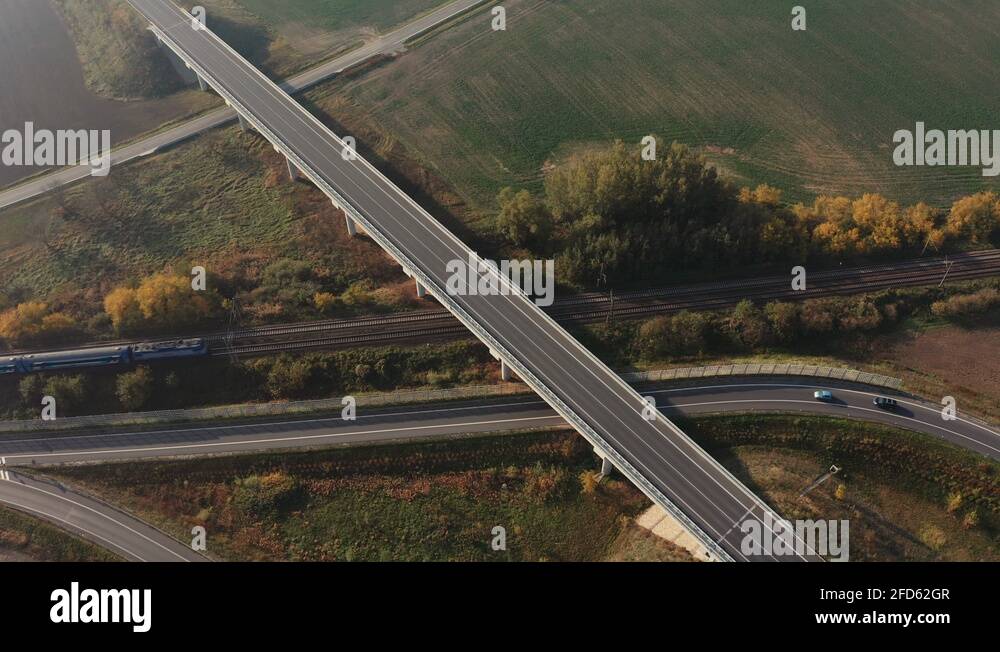 Train passing under a freeway bridge intersection - Aerial top view ...