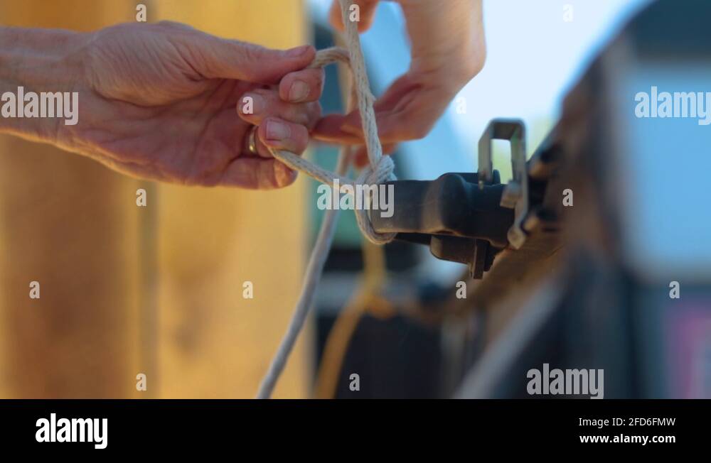 Old white man's hands securing a load in the back of the truck tying a ...