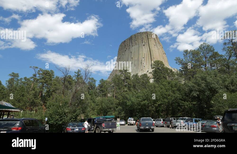 Steady wide shot of the Devils Tower, with cars of the visitors parked ...
