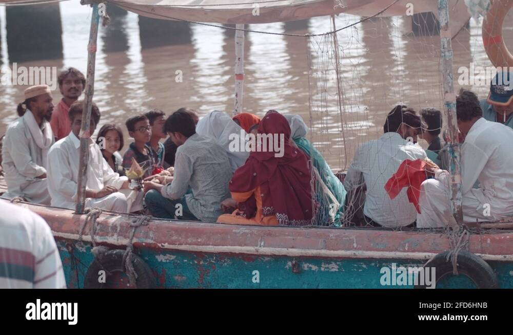 Hindu priest takes a group of people on boat to perform a traditional ...