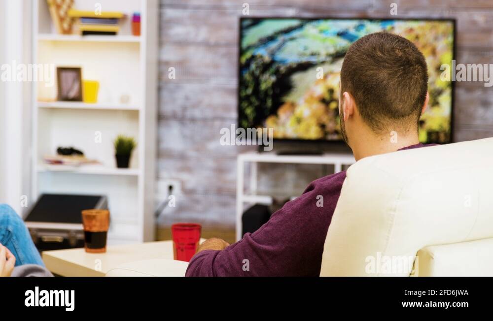 Back view of young man sitting on chair eating popcorn Stock Video ...
