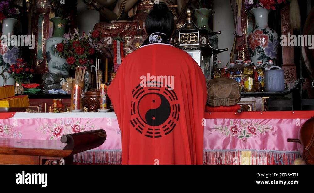A Taoist female monk wearing a red robe with the yin-yang symbol at the ...