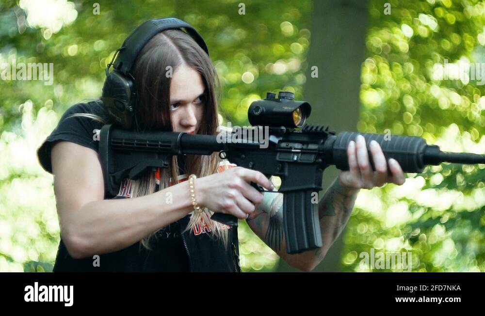 An attractive female shooting an assault rifle with red dot / reflex ...