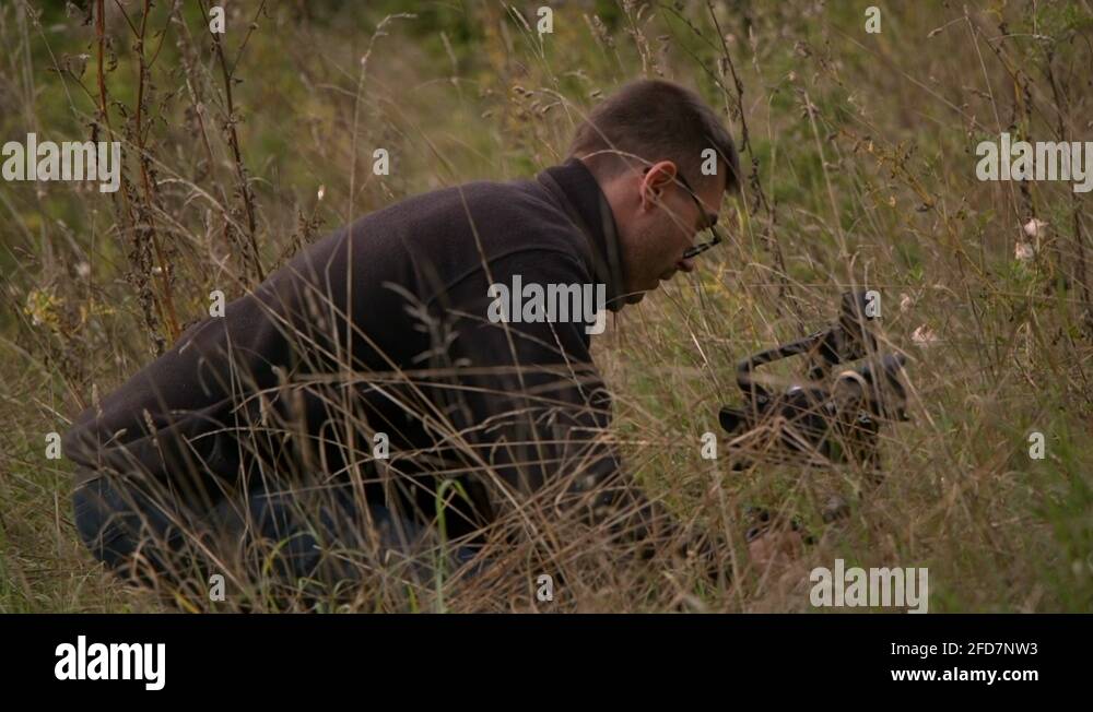Adult man in tall grass using a gimbal to film some nature shots Stock ...