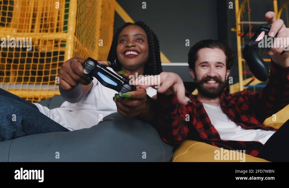Friends playing game on console with joysticks together indoors Stock ...