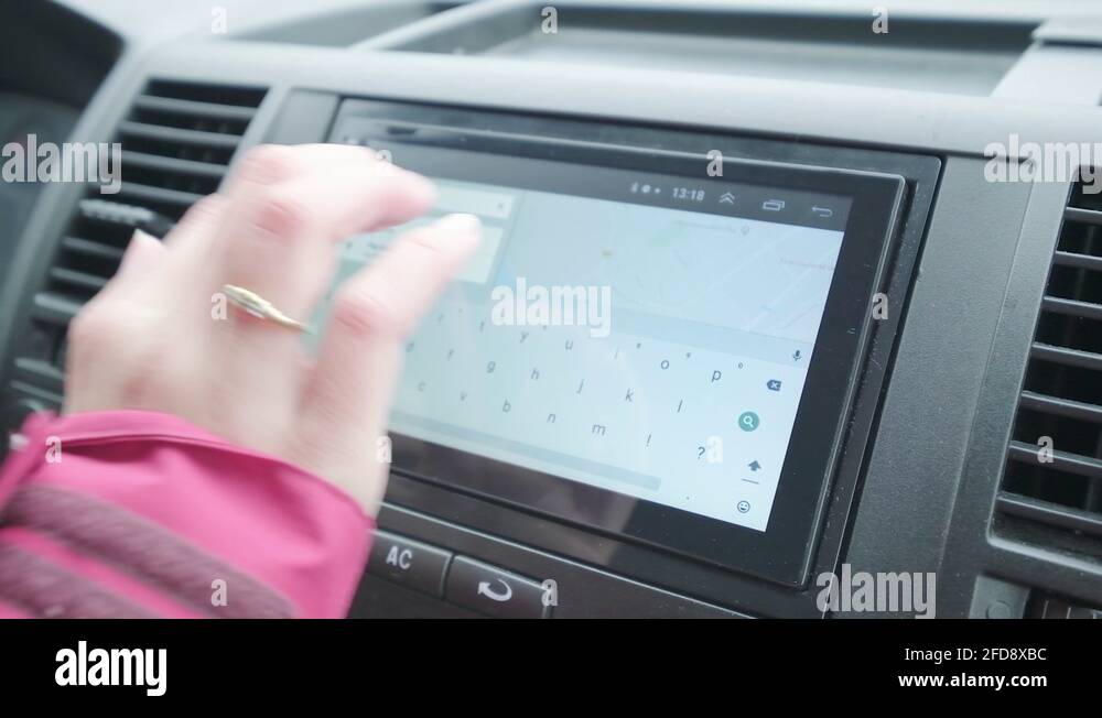 Lady typing in to the inbuilt GPS in the car of a campervan. Touching ...