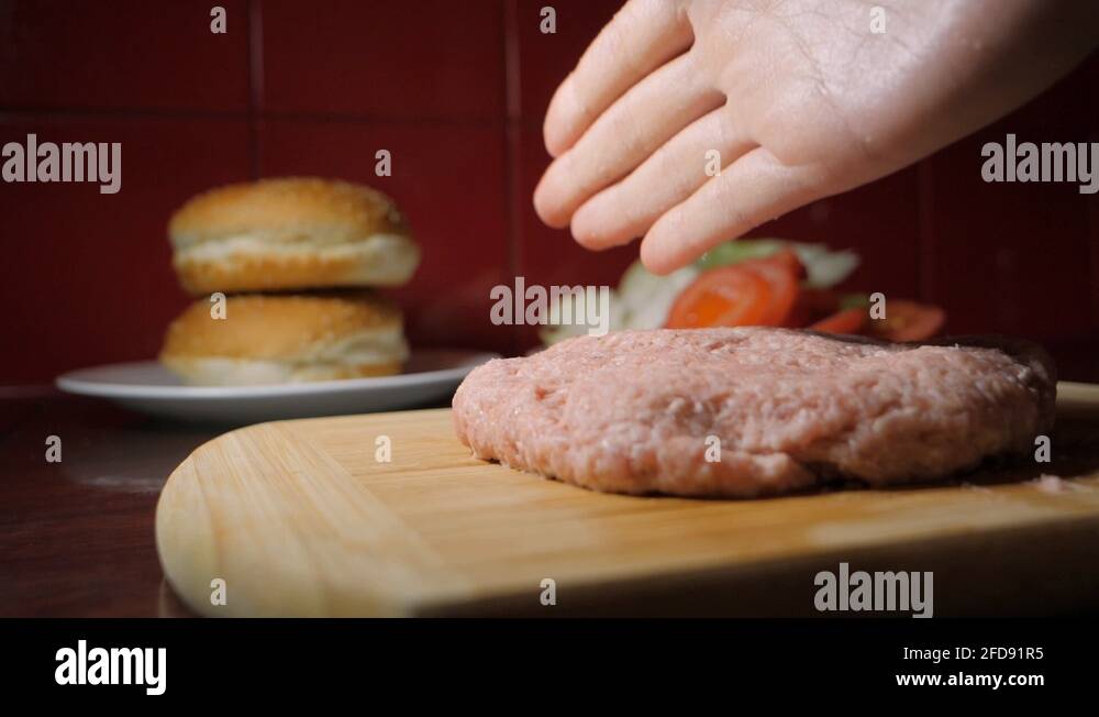 Slow motion person using their hand to split a lump of mince meat into ...