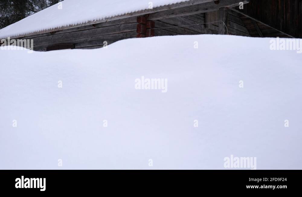 Tilt up behind pile of snow, reveal cozy log cabin, Roof covered in ...