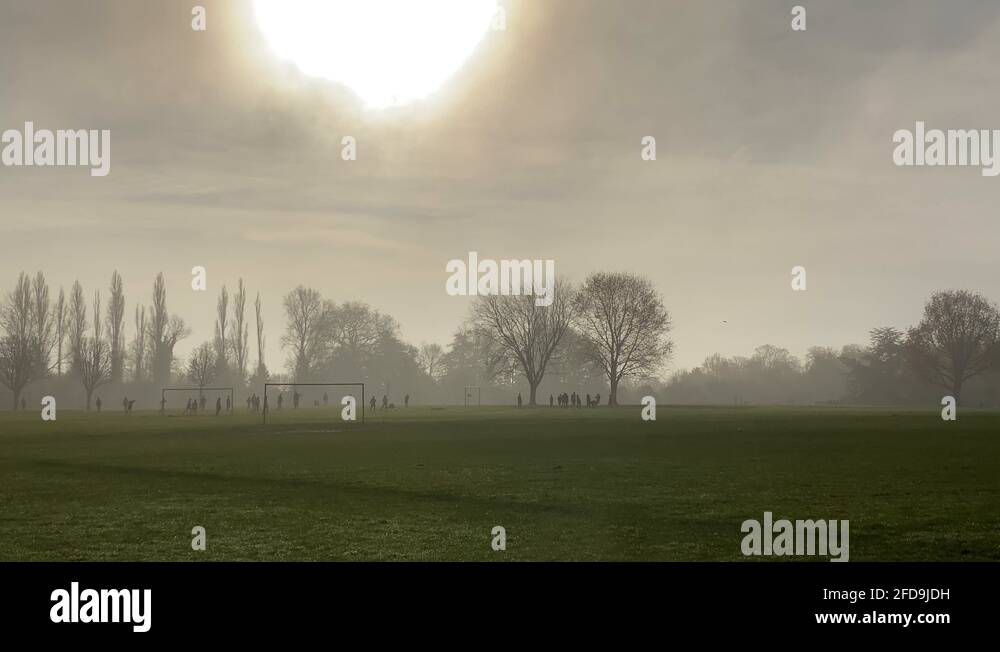 Kids playing football in the park, backlit by the sun, wide shot Stock ...