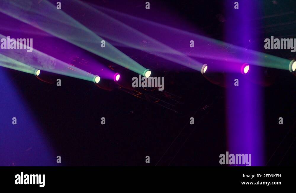 Plenty of different sized stage lights mounted to a ceiling illuminate ...