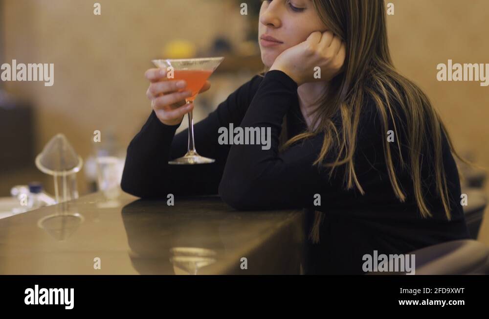 Lonely, drunk and heartbroken woman having a drink alone in a bar. 4K ...