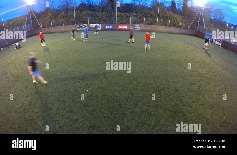 Teams of football playing on a compact pitch from dusk to evening, time ...