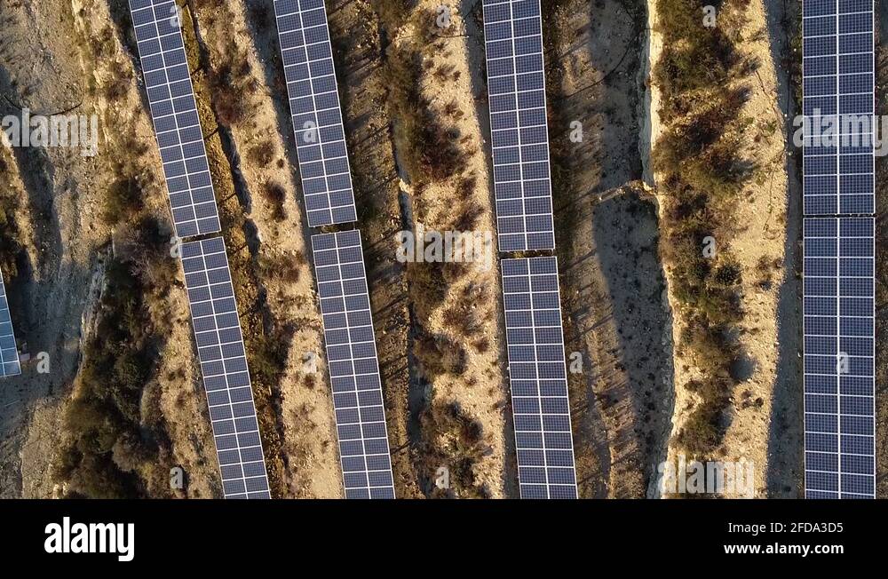 Wide top-down view of a large solar farm installed in a dry desert-like ...