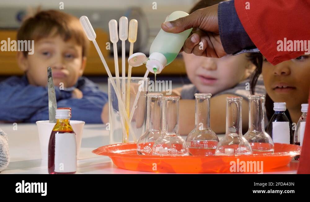 Curious students watching science teacher conducting experiment in ...