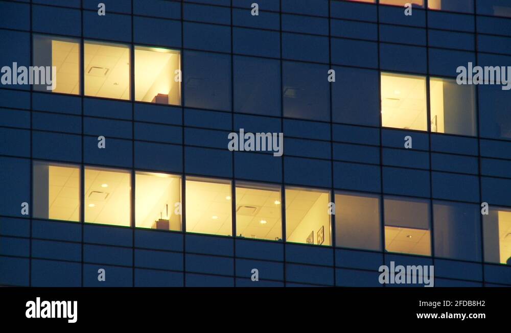 Office lights inside a tall building in New York City shine and give ...