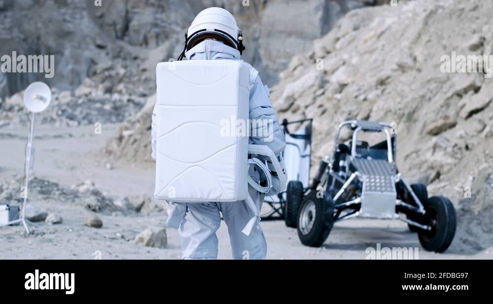 Back view on the NASA spaceman in the full equipped armor walking ...