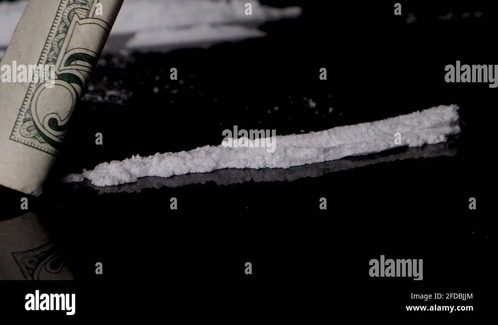 Snorting cocaine line with a rolled banknote, isolated on smooth black ...