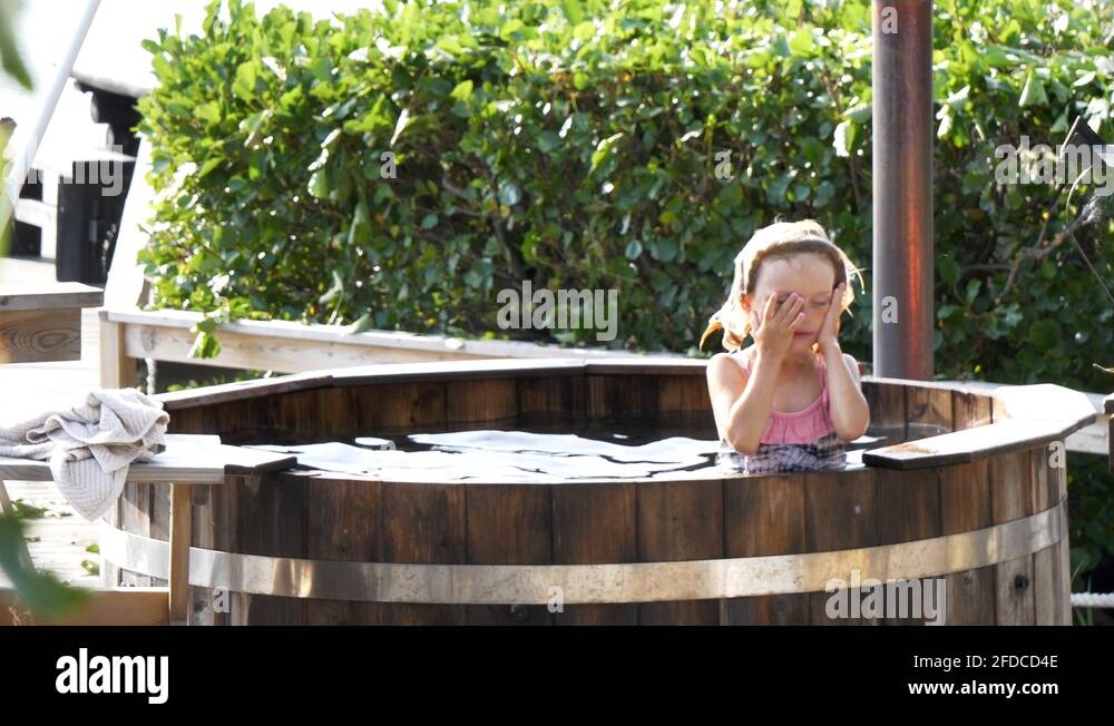 Little girl takes a bath in tub while thinking of an idea. Slow motion ...