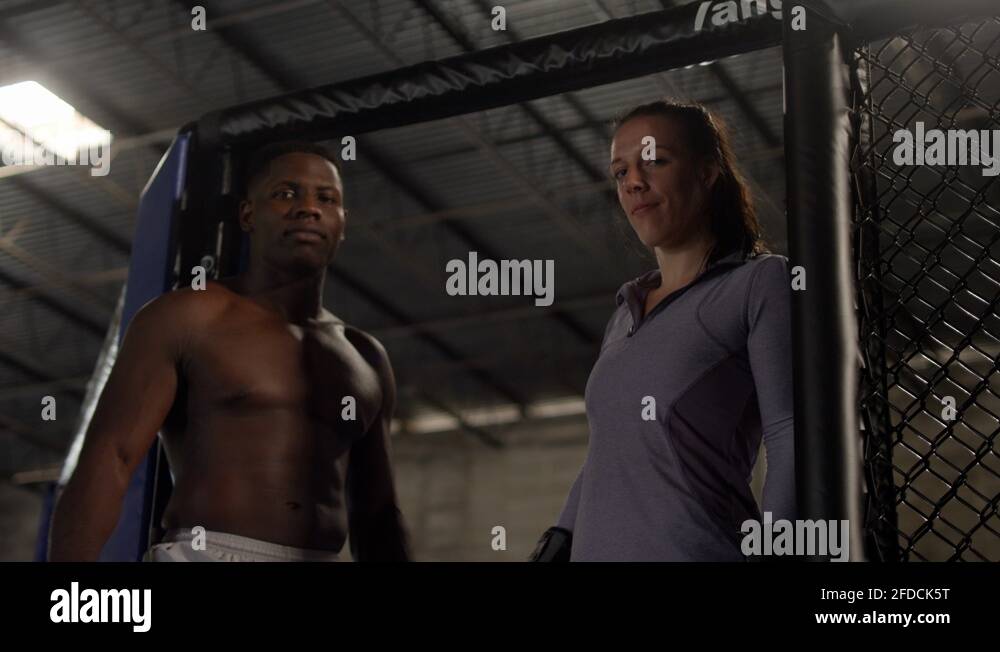 Male and female MMA fighters stare into camera from entrance to octagon ...