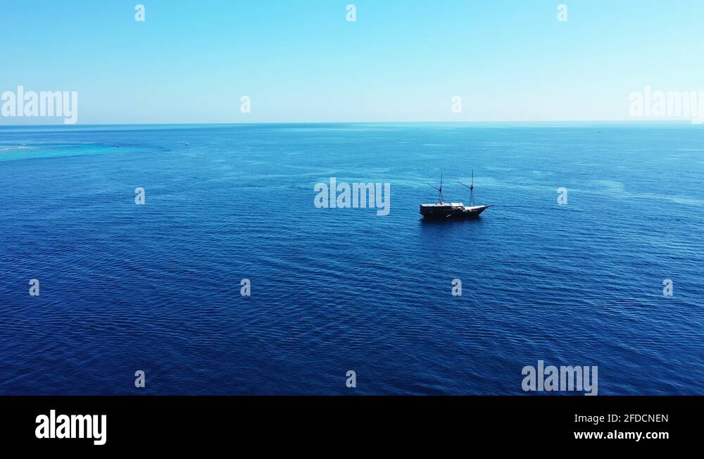 An isolated ship on the surface of the vast expanse of vibrant blue ...