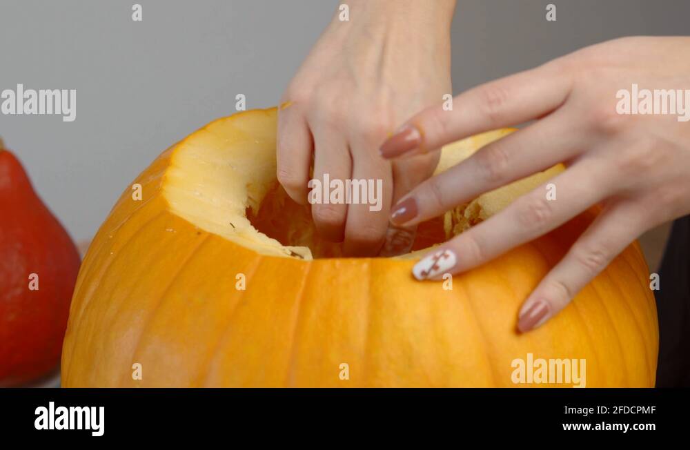 A Woman Scraping The Guts And Seeds Using A Spoon Inside The Pumpkin ...