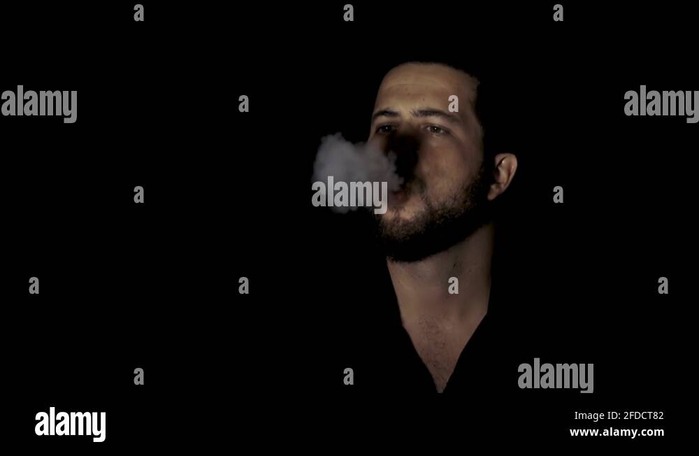 Man disappearing behind cigarette smoke, black background Stock Video ...