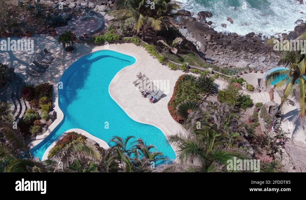 Drone top-down view of two men hanging out around a pool at a luxury ...