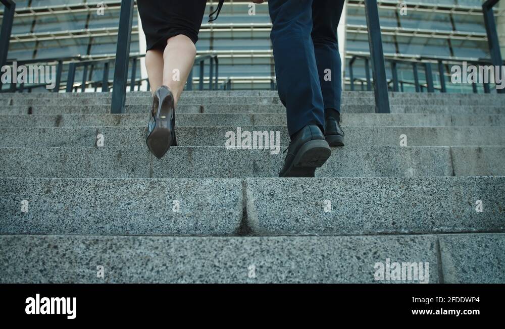Back view business couple going upstairs. Legs walking at stairs in ...