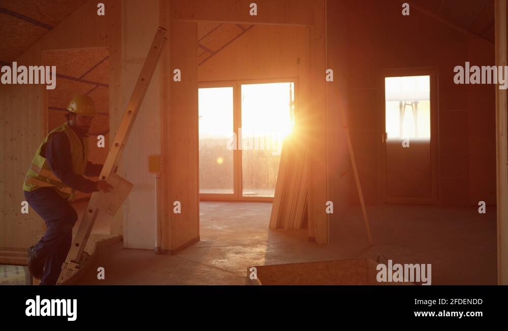 LENS FLARE: Young builder climbs up ladder into sunlit floor under ...