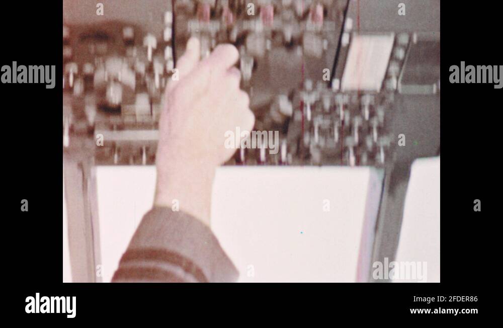 1960s: Pilot turns knobs in cockpit. Stewardess talks to seated ...