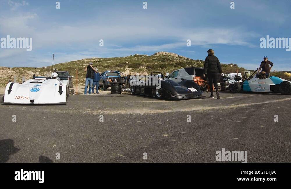 A Woman Checking On The Black Racing Car Parked At The Roadside Of The ...