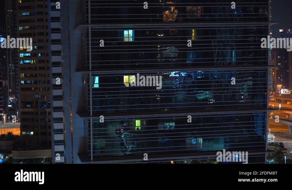 High rise modern building facade with lights in windows at night ...