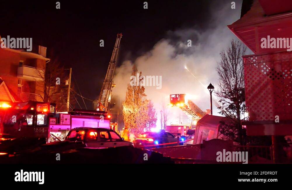 Structure fire scene with smoke, firetrucks ladders and police cars ...