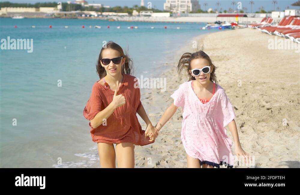 Little happy funny girls have a lot of fun at tropical beach playing ...