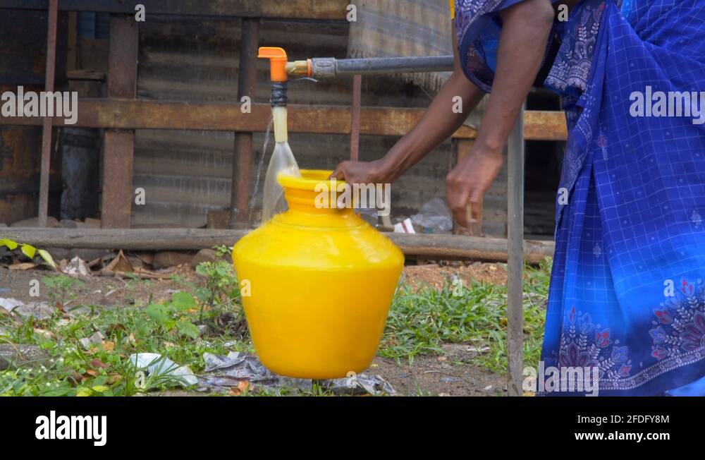 Poor Indian woman washes water vessel, communal water tap, water crisis ...