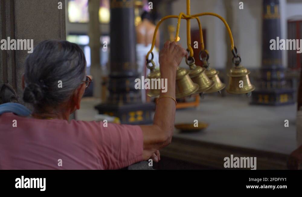 Old devotee religious Indian woman rings bells, Hindu temple ceremony ...