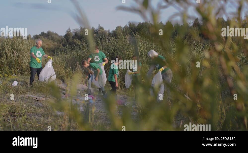 Caucasian family of parents, grandparents and children cleaning field ...