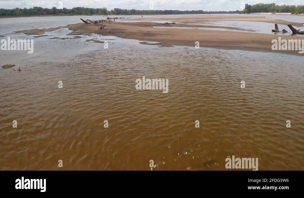 Aerial fast low pass over the shrinking river with old wood laying in ...