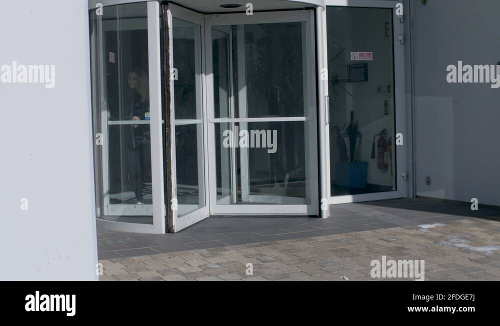 Female employee leaves office building through a revolving door after ...