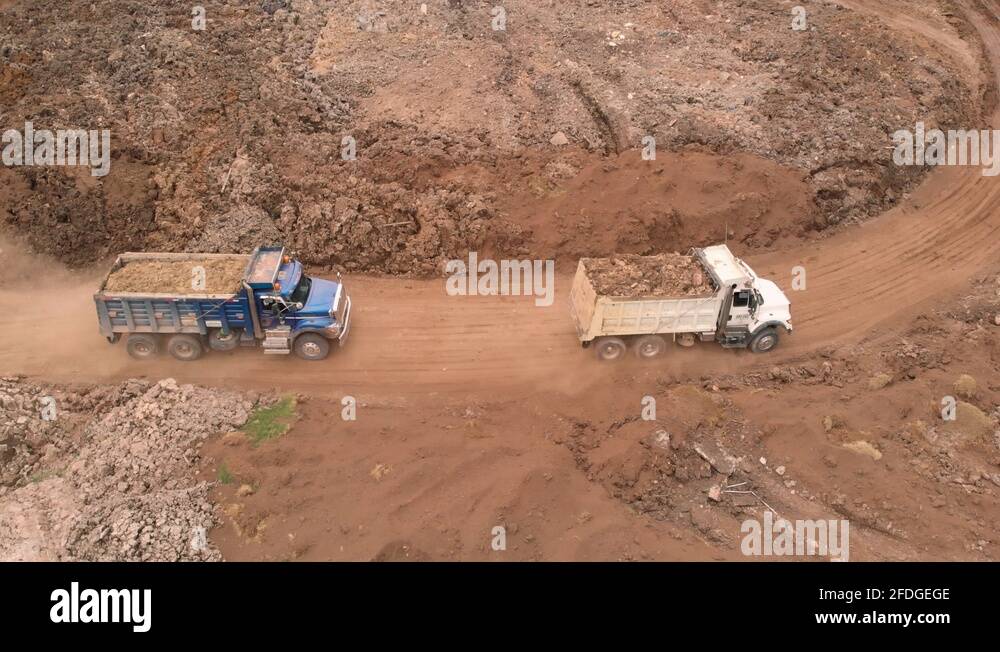 Dump trucks carrying earth, soil and dirt at the landfill site. Aerial ...